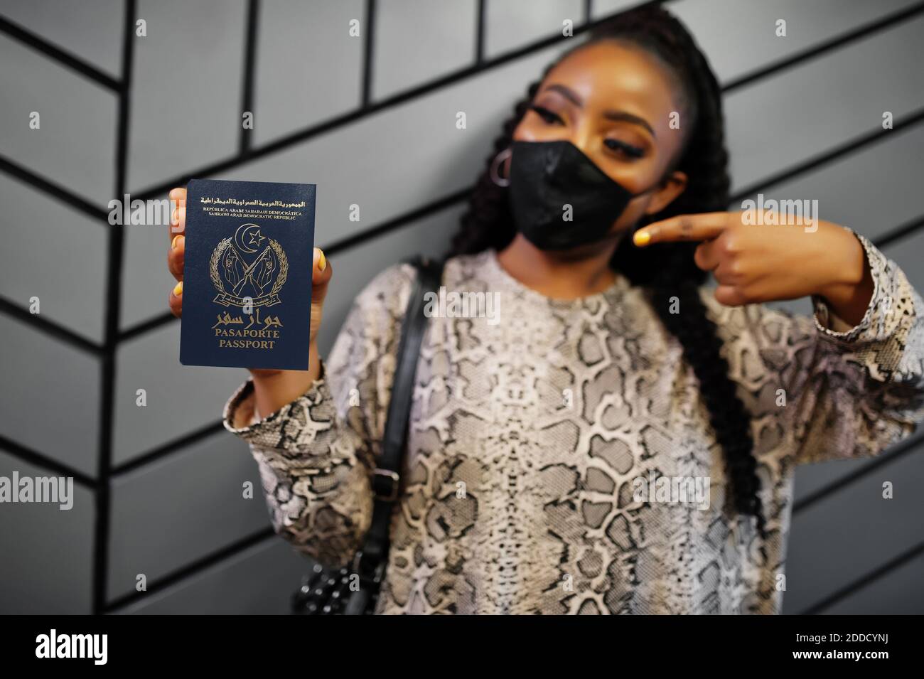African woman wearing black face mask show Western Sahara passport in ...