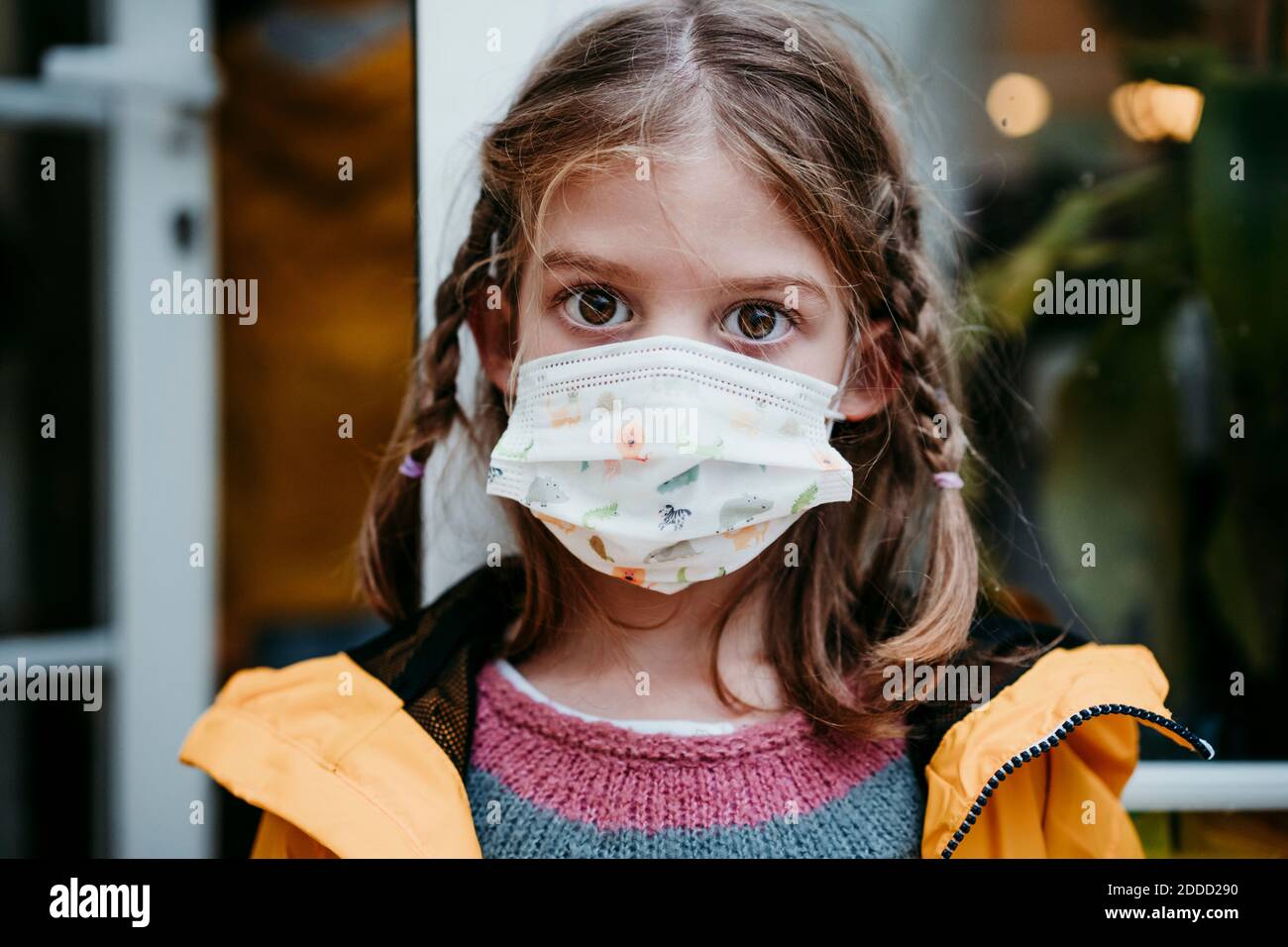 Girl wearing face mask while standing against door Stock Photo - Alamy
