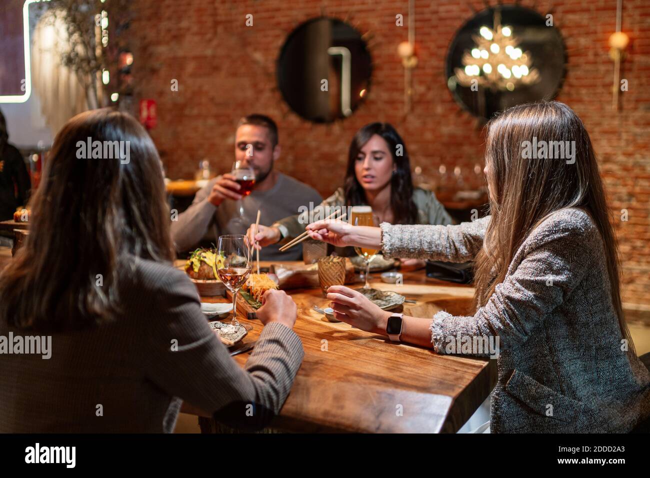 Friends having drink and food while sitting by table at restaurant ...