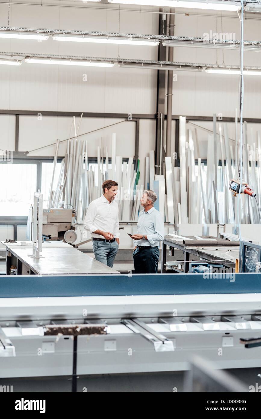 Male engineers discussing while standing in manufacturing industry ...