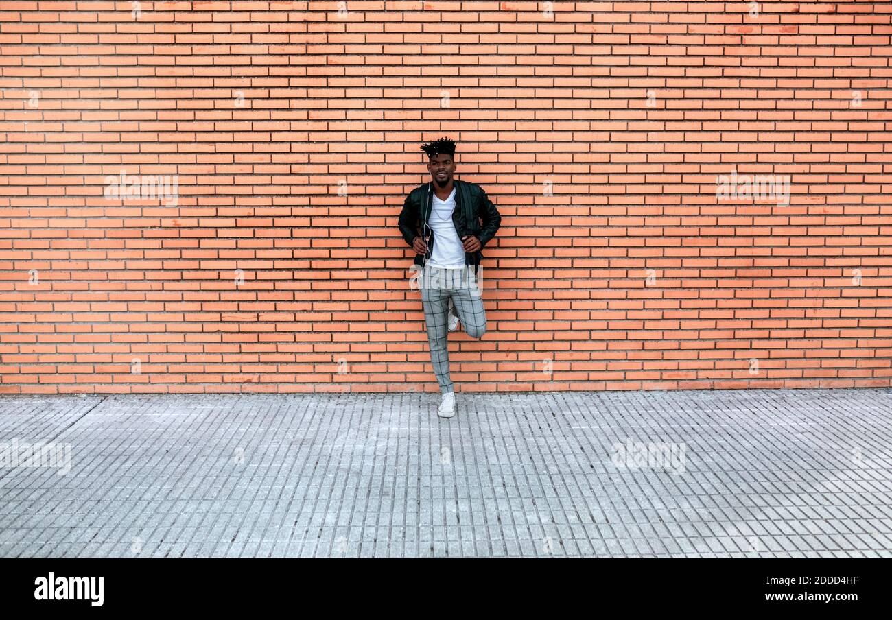 Mid adult man wearing leather jacket standing against brick wall Stock ...