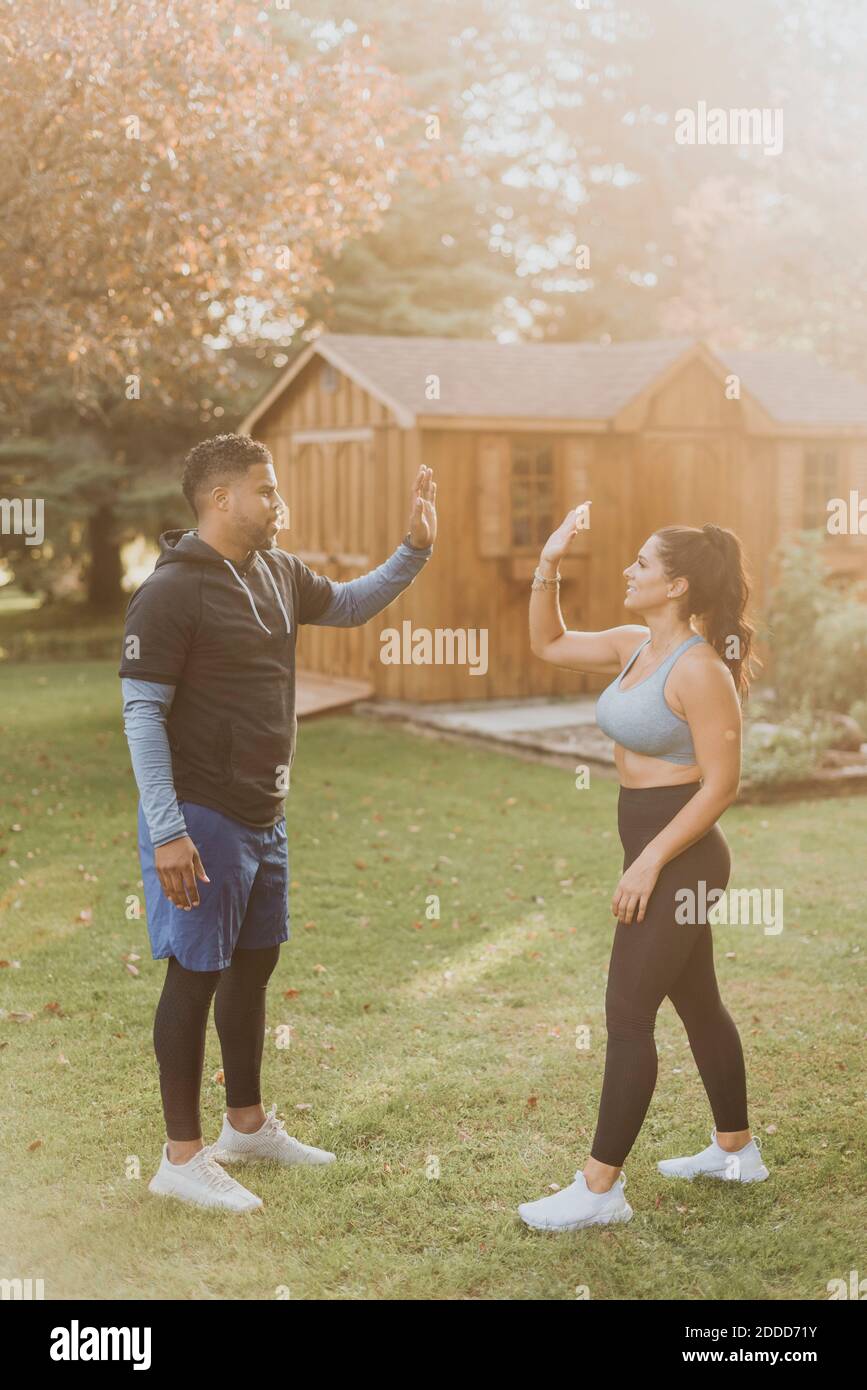 Boyfriend and girlfriend giving high five while standing at backyard ...