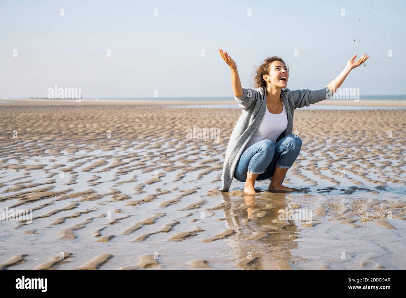 Playful young woman throwing water at seashore Stock Photo - Alamy