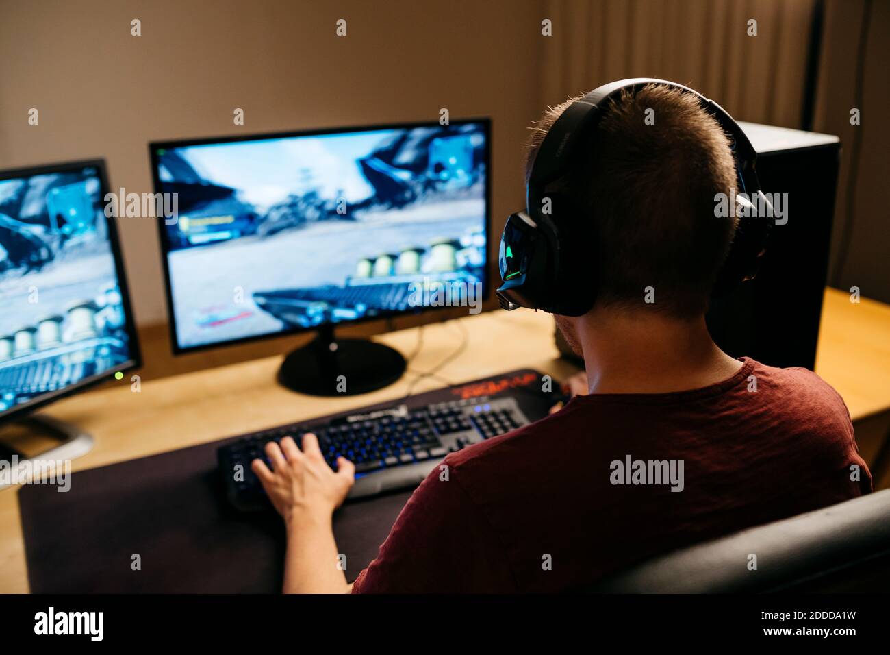 Young man playing video games with computer at desk Stock Photo - Alamy