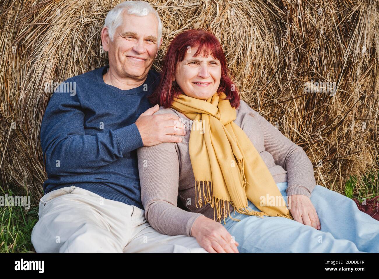 Happy senior couple resting against hay bale at field Stock Photo - Alamy