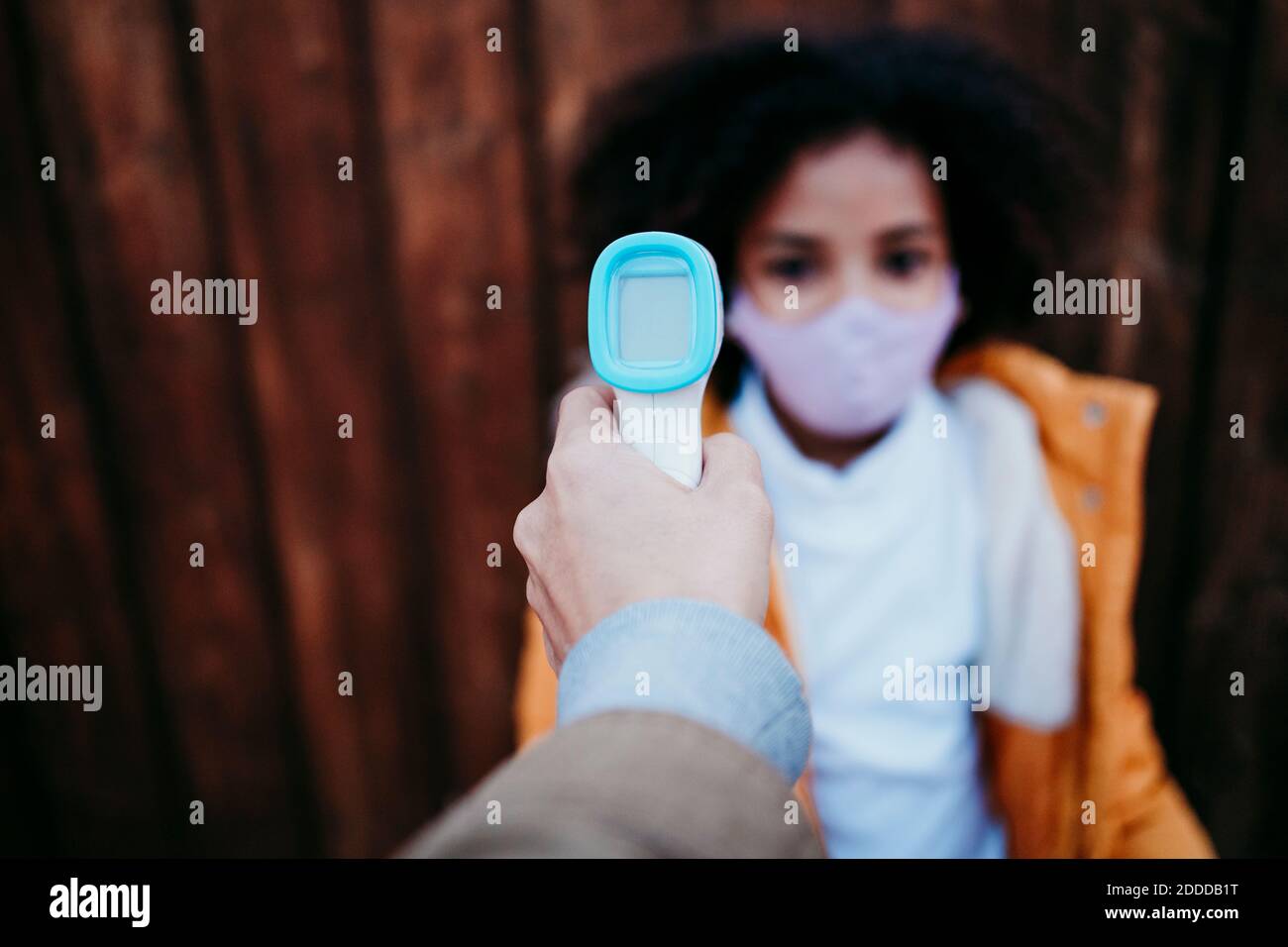 Woman using infrared thermometer while checking girl temperature ...