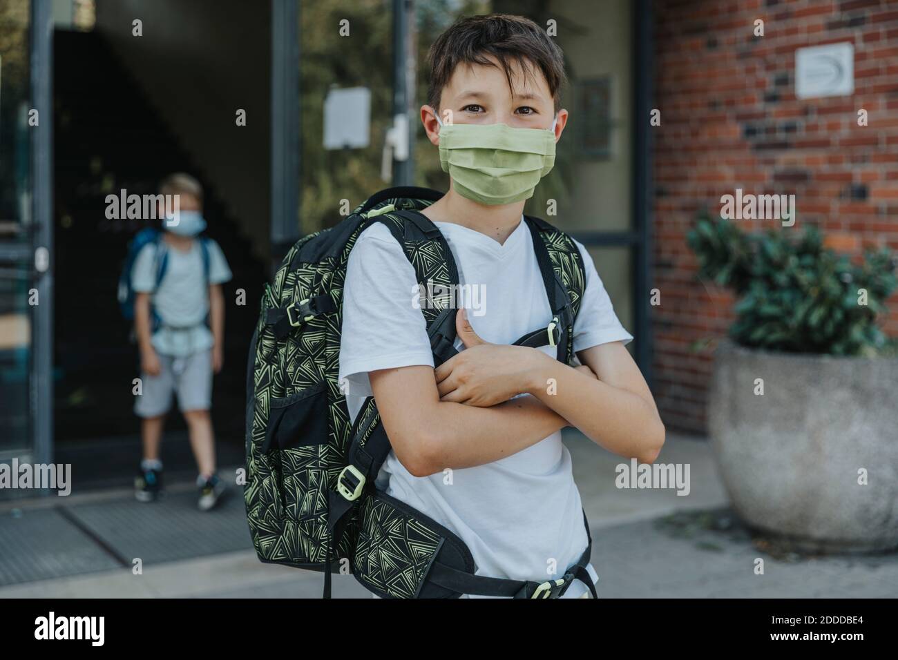 Little boy wearing protective face mask with arms crossed standing in ...