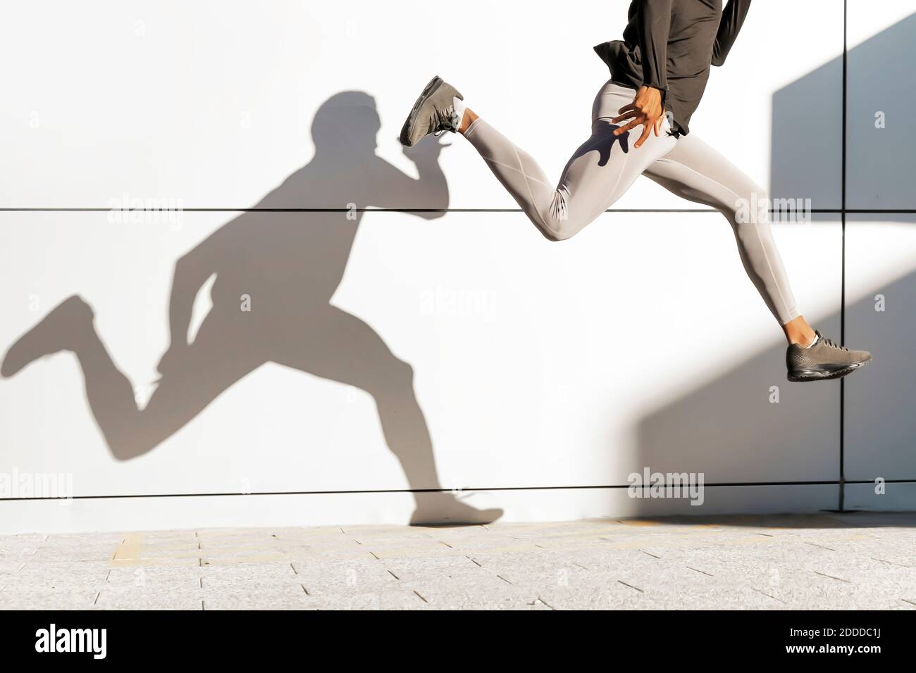 Young man running against white wall Stock Photo - Alamy
