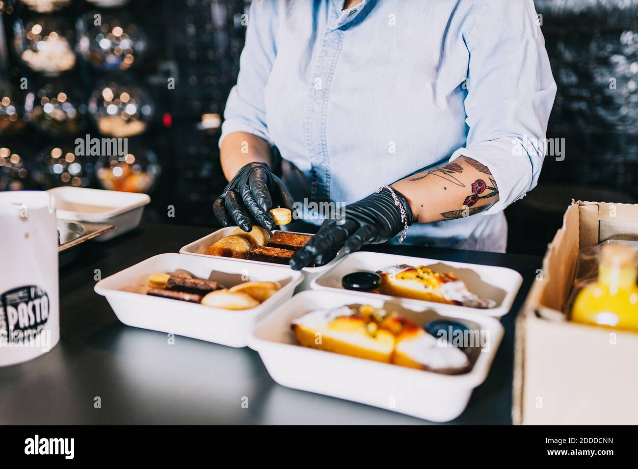 Midsection of female chef preparing take out containers at counter in ...