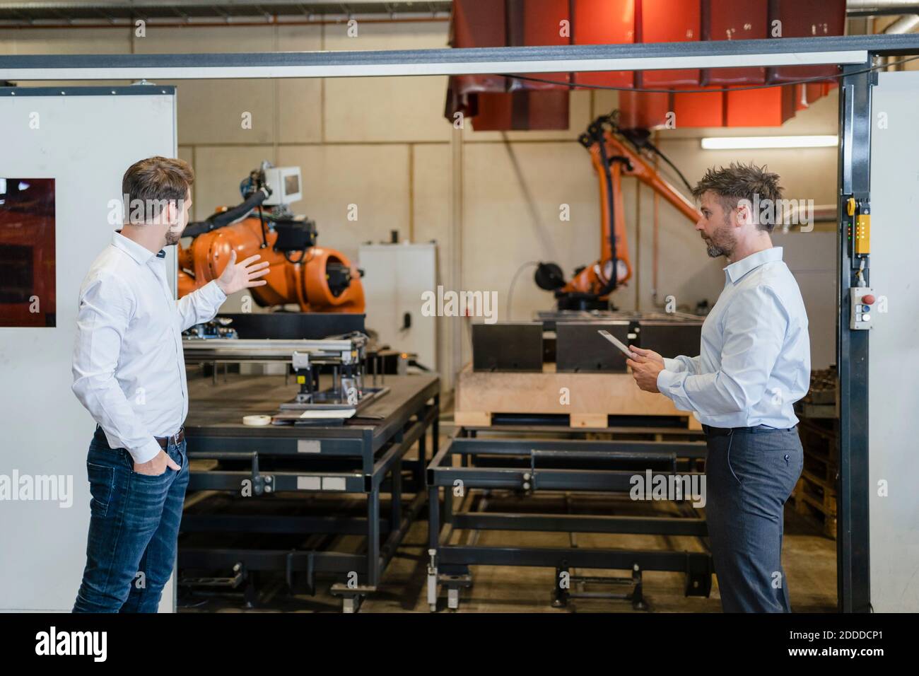 Businessman having discussion with colleague while standing by robotic ...