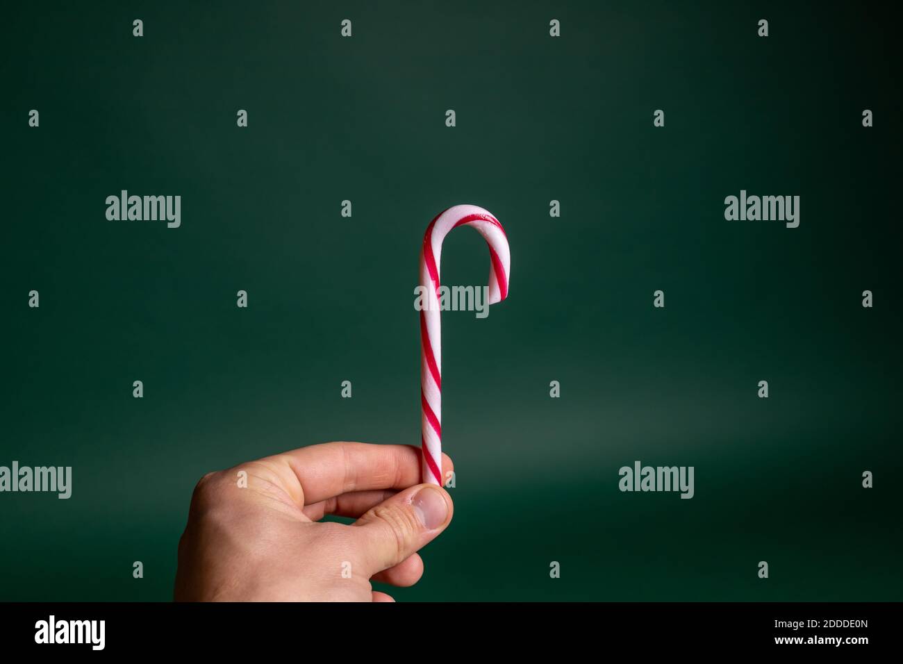 hand holding candy cane on green background Stock Photo - Alamy