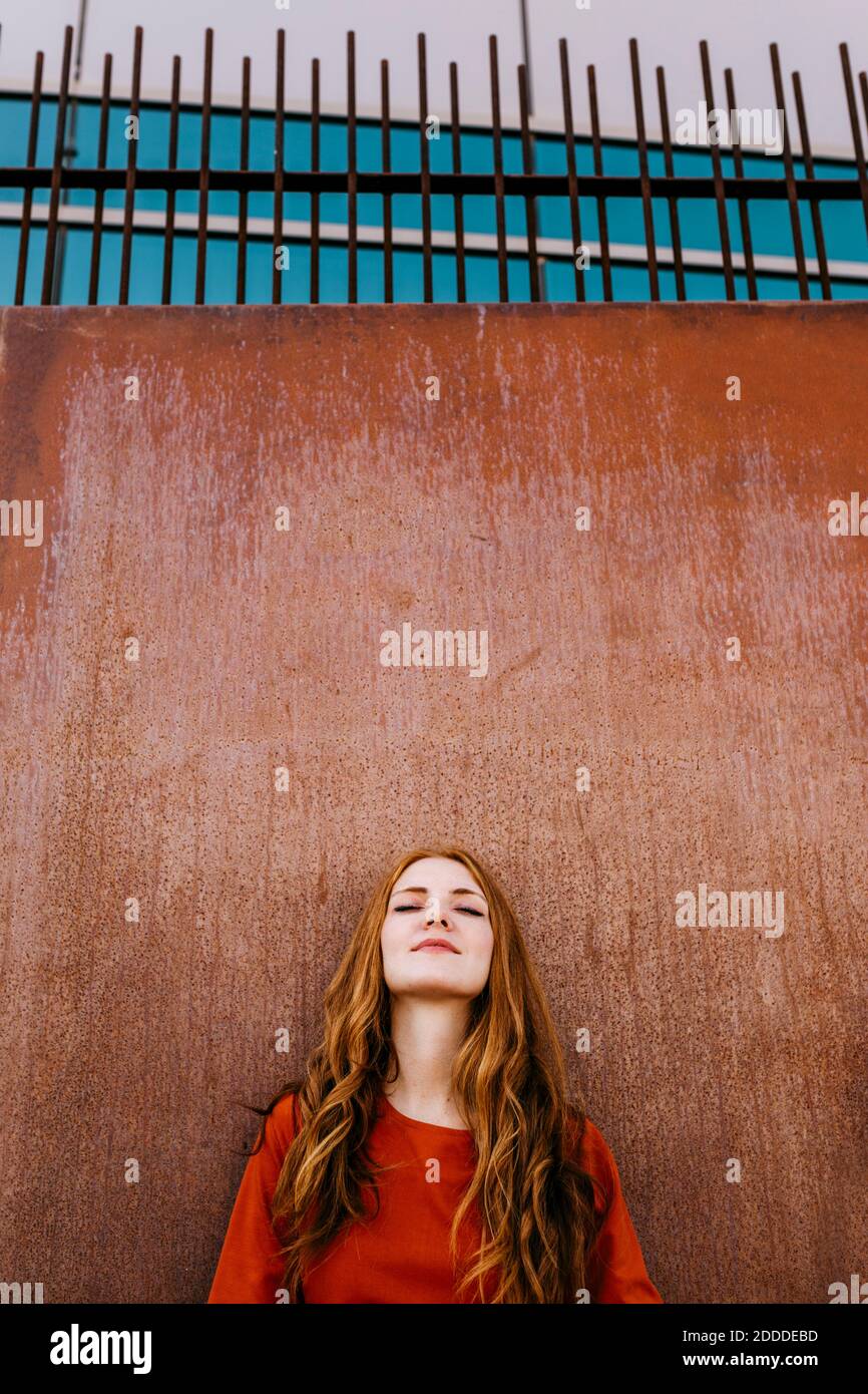 Redheaded beautiful woman leaning against a wall outdoors Stock Photo ...