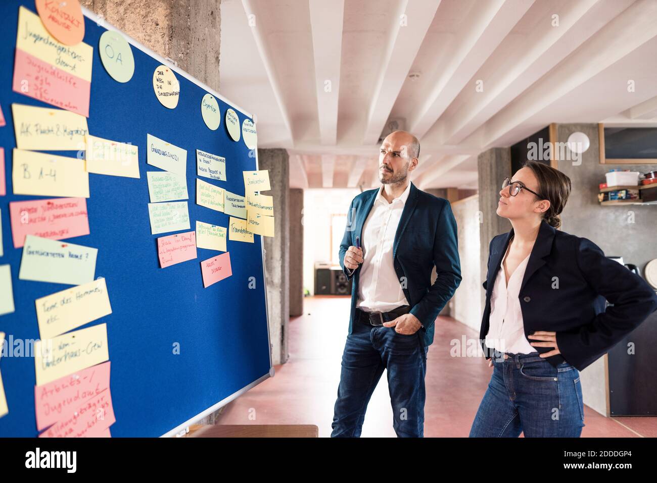 Businessman and woman reading note putted on bulletin board while ...