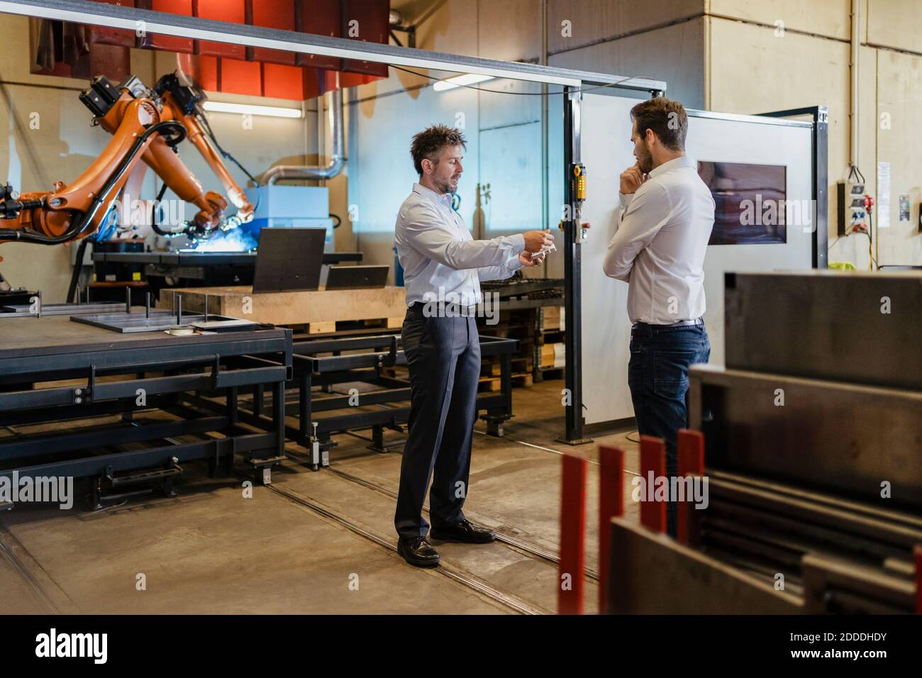 Young and mature businessman having discussion while standing against ...