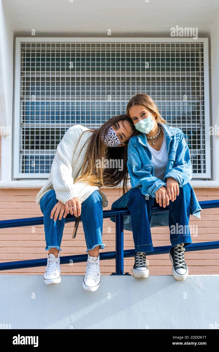 Teenage girl head on female friend's shoulder sitting during sunny day ...