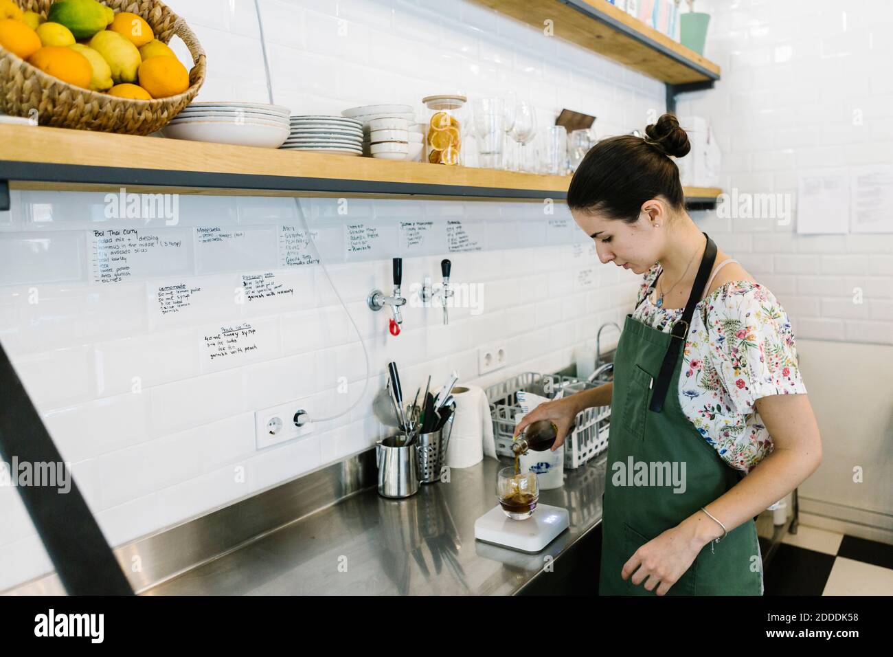 Barista making cold brew coffee while standing in kitchen at coffee ...