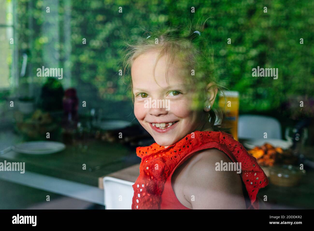 Smiling girl looking through window on sunny day Stock Photo - Alamy