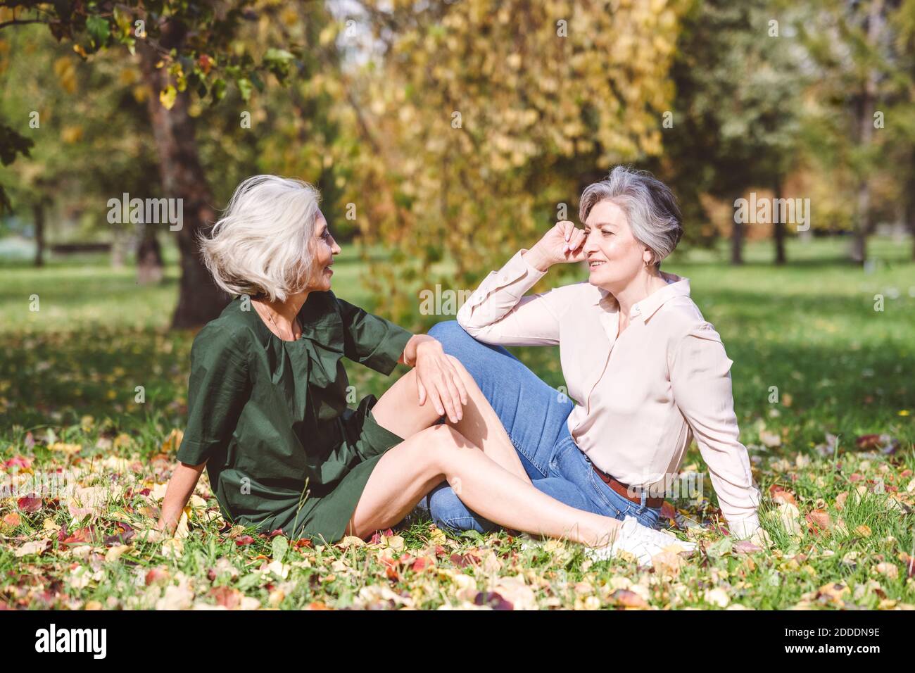 Mature women talking while sitting at park Stock Photo - Alamy