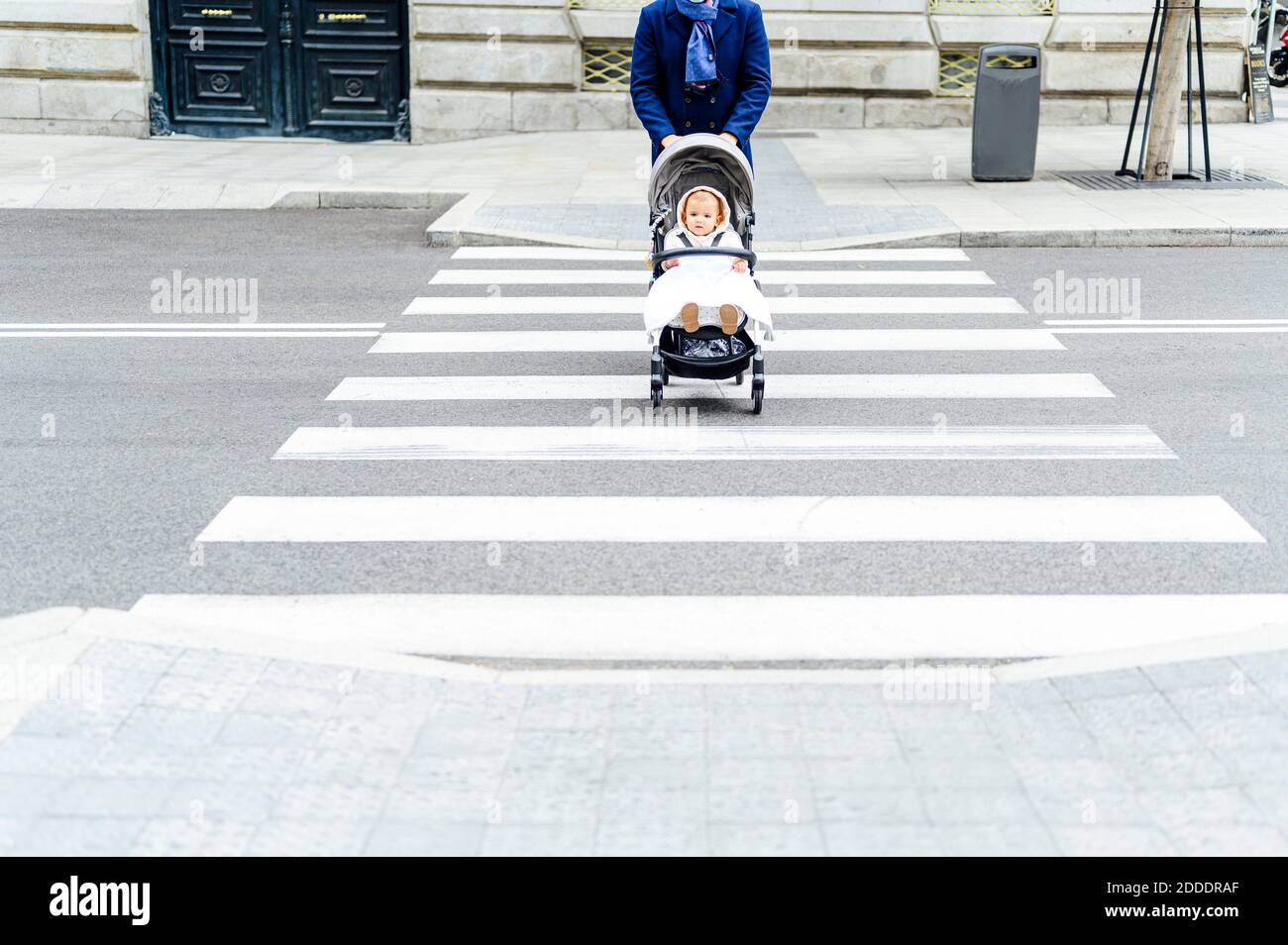 Man walking with baby stroller while crossing road in city Stock Photo ...