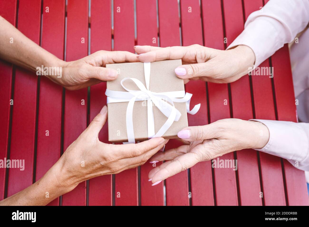 Woman giving gift to female friend at table in restaurant Stock Photo ...