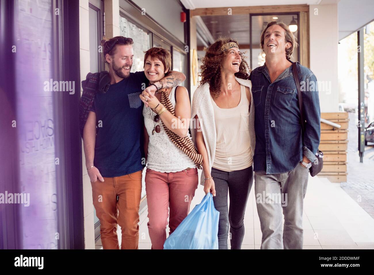 Smiling friends walking on street in city Stock Photo - Alamy