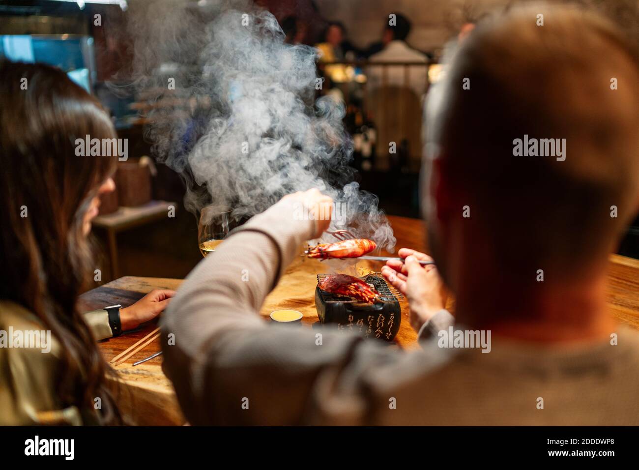 Man holding food while sitting by table at restaurant Stock Photo - Alamy