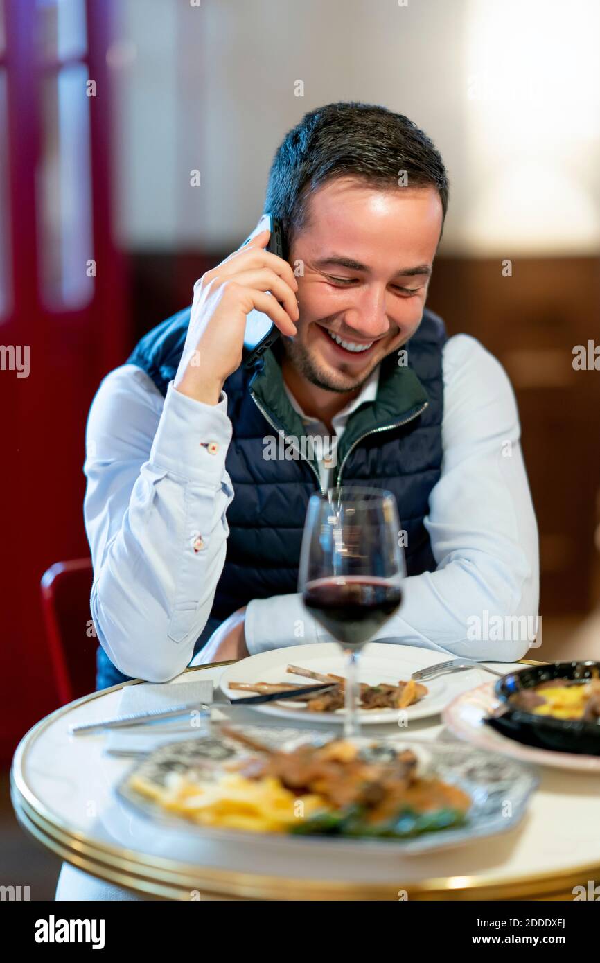 Young man talking on smart phone at dining table of restaurant Stock ...