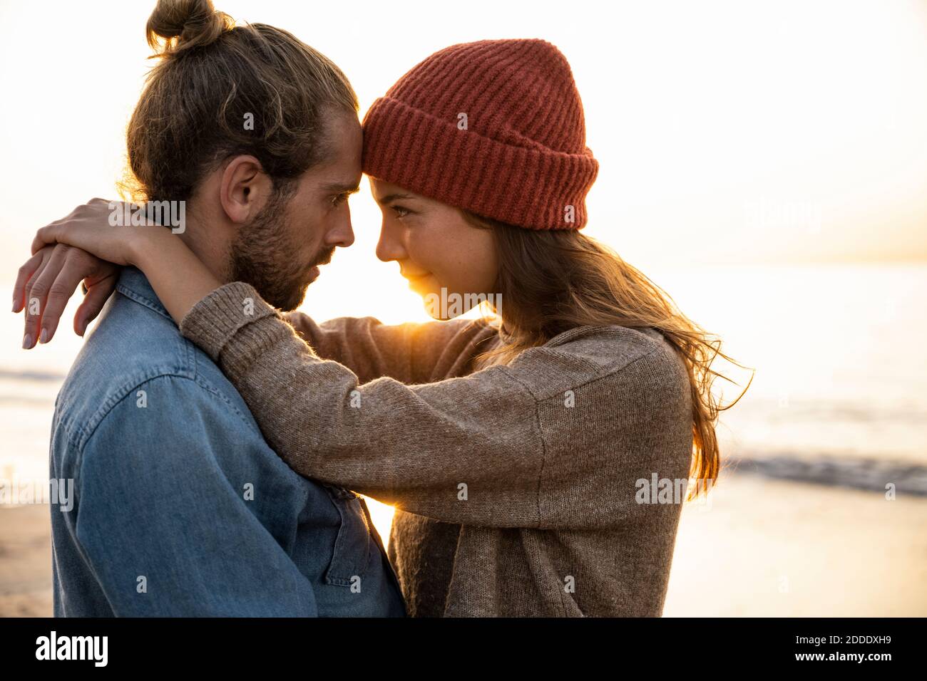 Loving young couple standing face to face at beach during sunset Stock ...