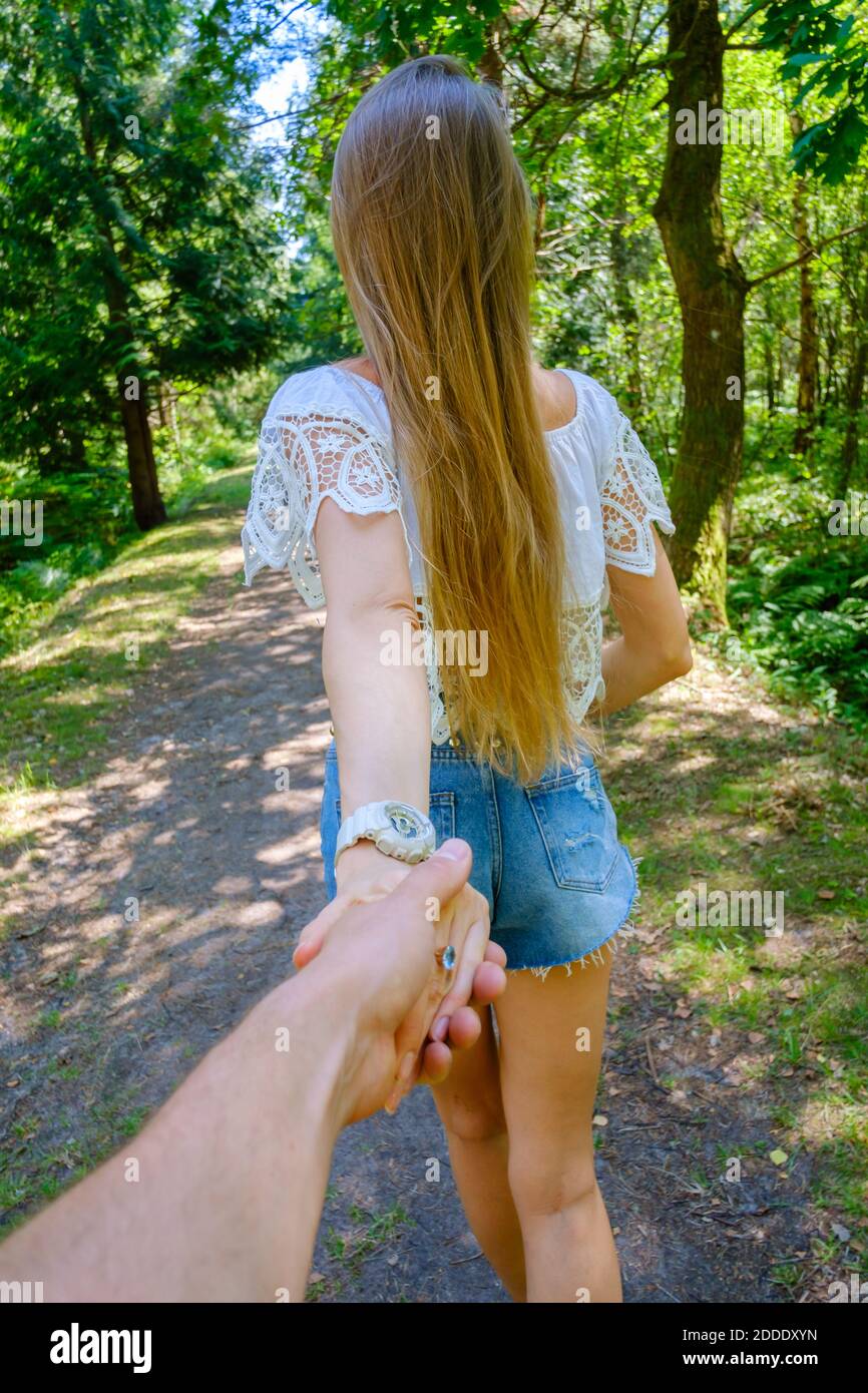 Young woman followed by boyfriend walking in forest Stock Photo - Alamy