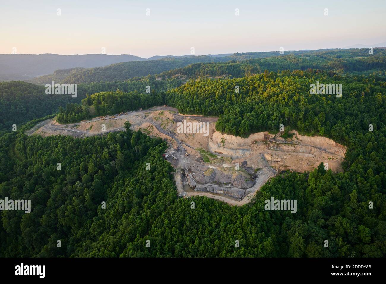Aerial view of quarry surrounded by green forest at dawn Stock Photo ...