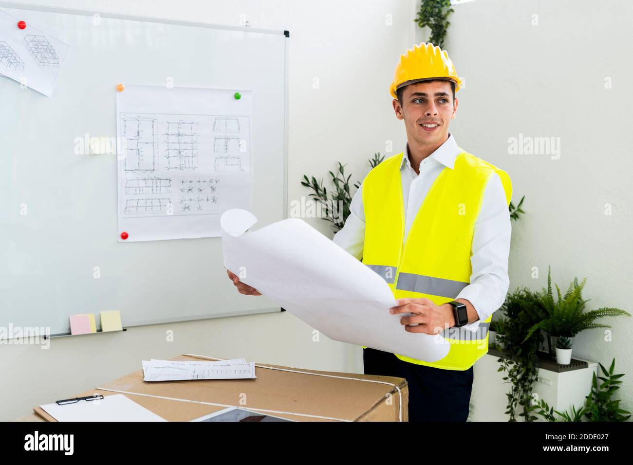 Handsome building contractor holding blueprint while looking away in ...