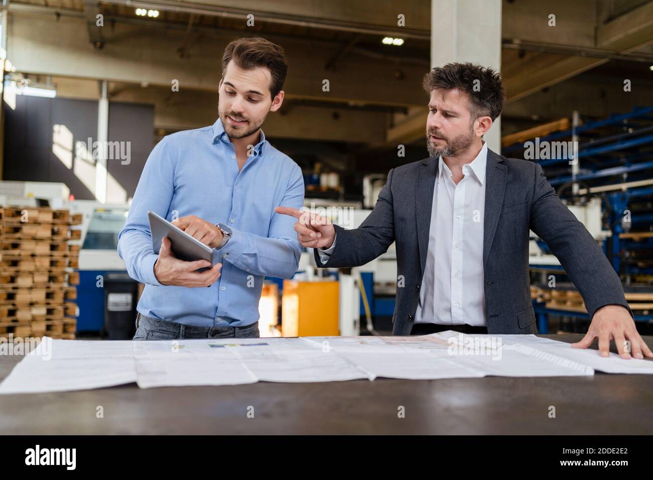 Businessmen using digital tablet while working at factory Stock Photo ...