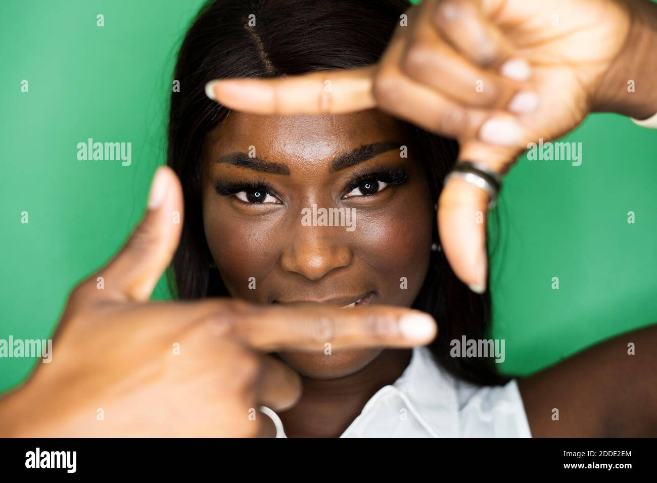 Young woman making finger frame against green background Stock Photo ...