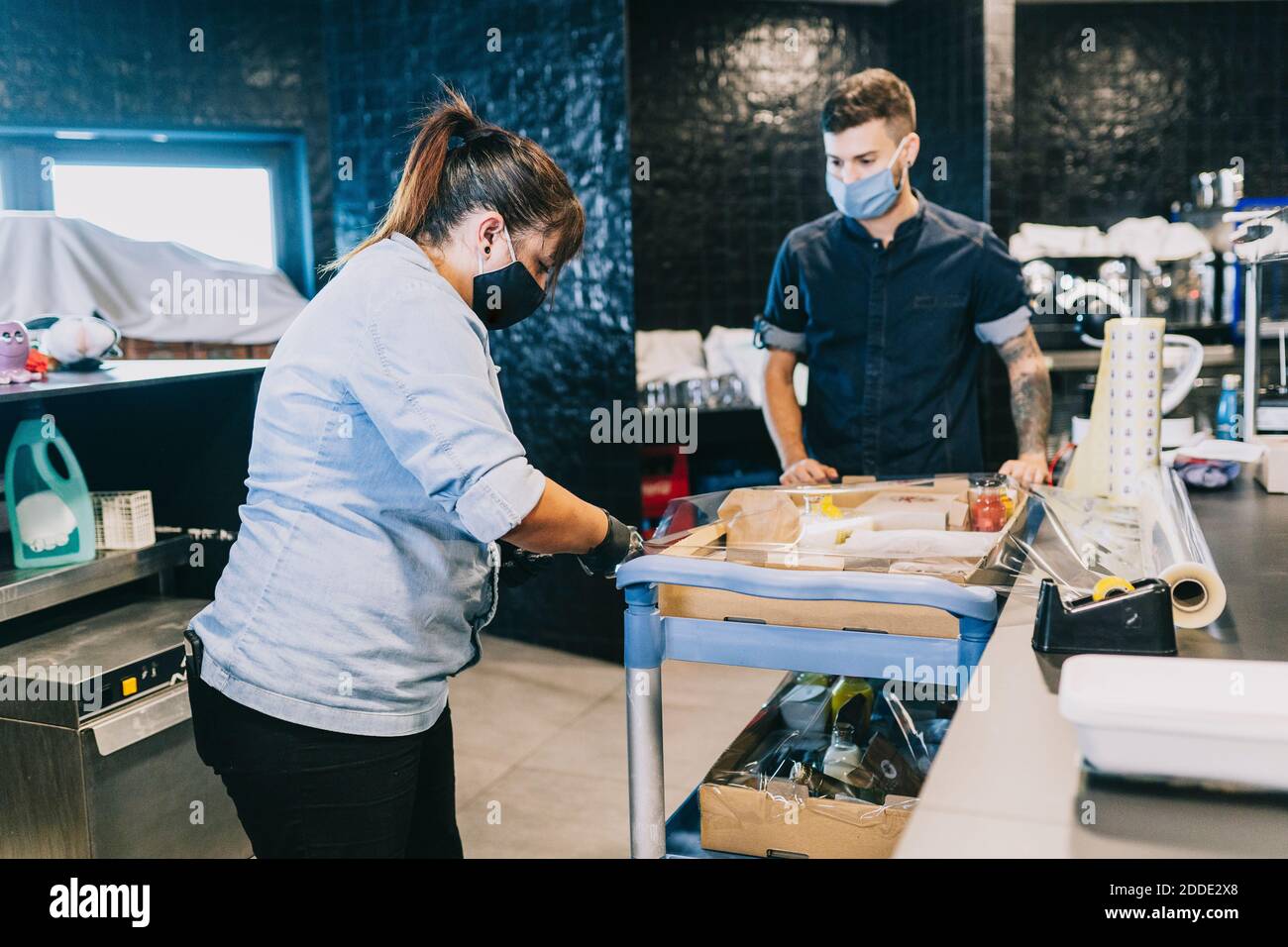 Mid adult male and female chefs working together for take out food ...