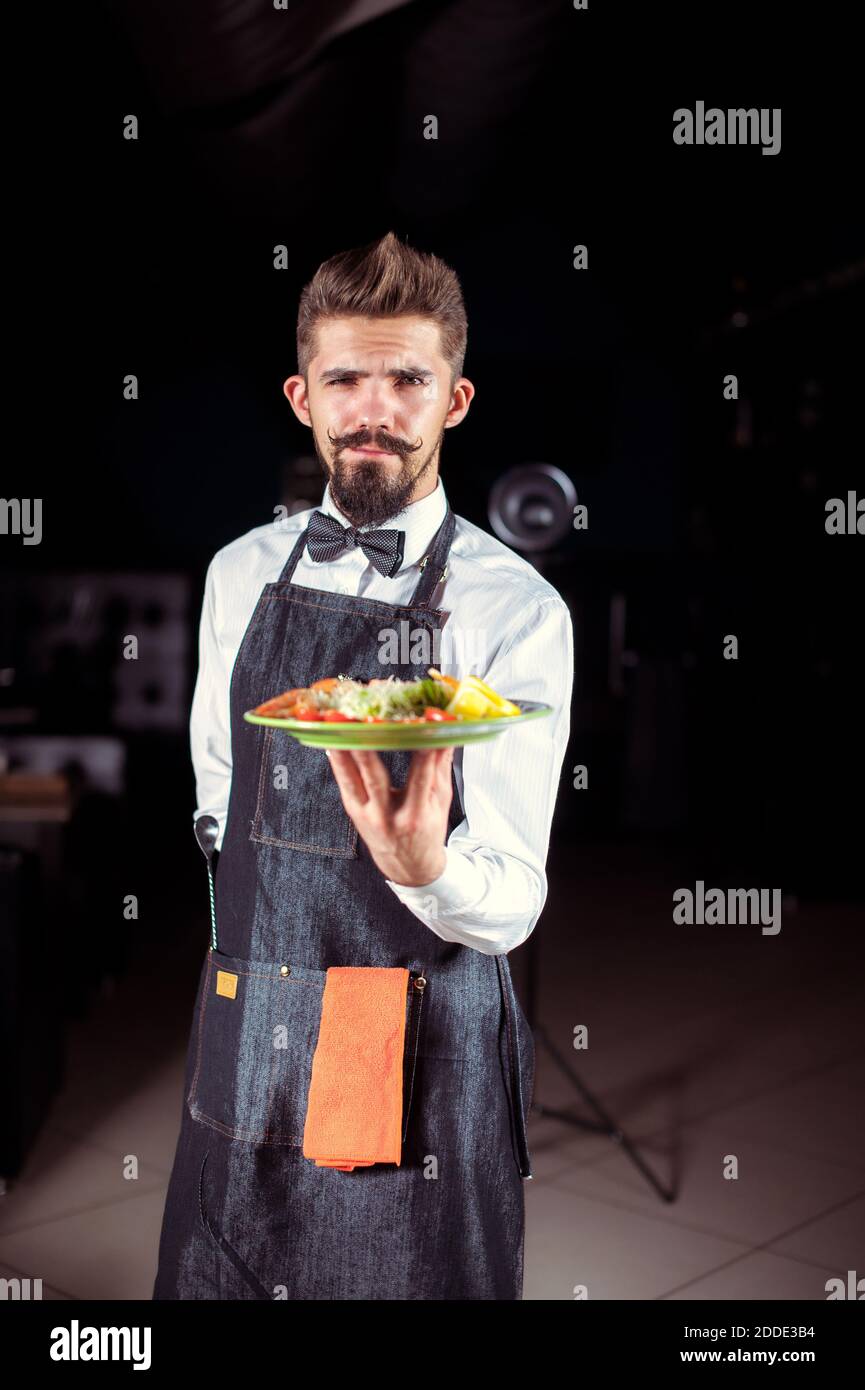 Professional friendly waiter helpfully serves dish in the restaurant ...
