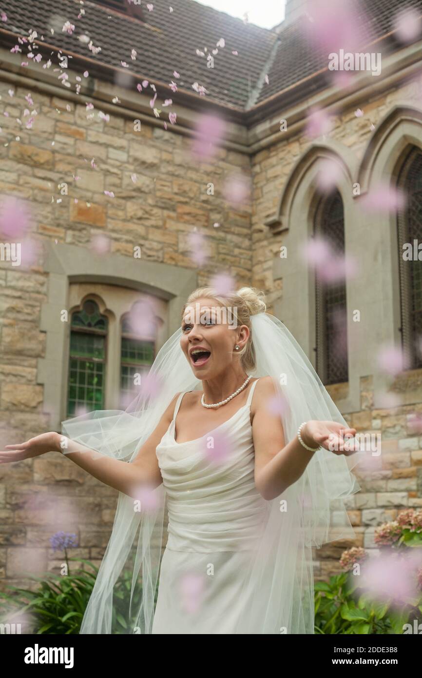 Surprised young bride standing amidst petal confetti at church Stock ...