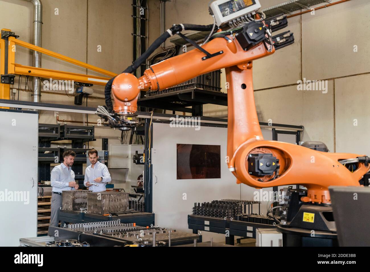 Automatic robotic arm machine with businessmen standing in background ...