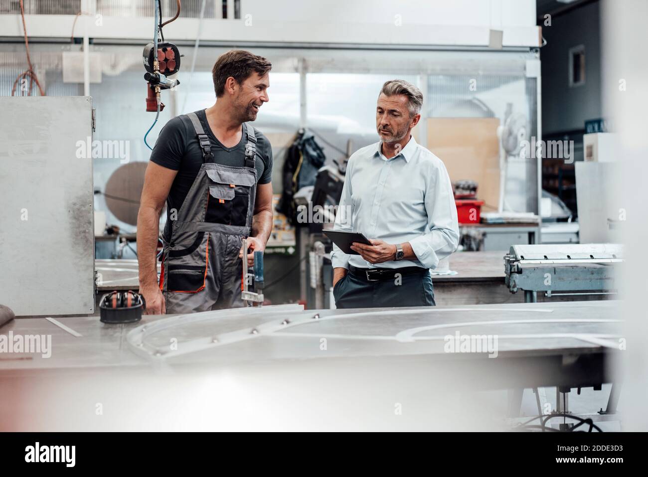 Engineer discussing with worker while standing by machinery in industry ...