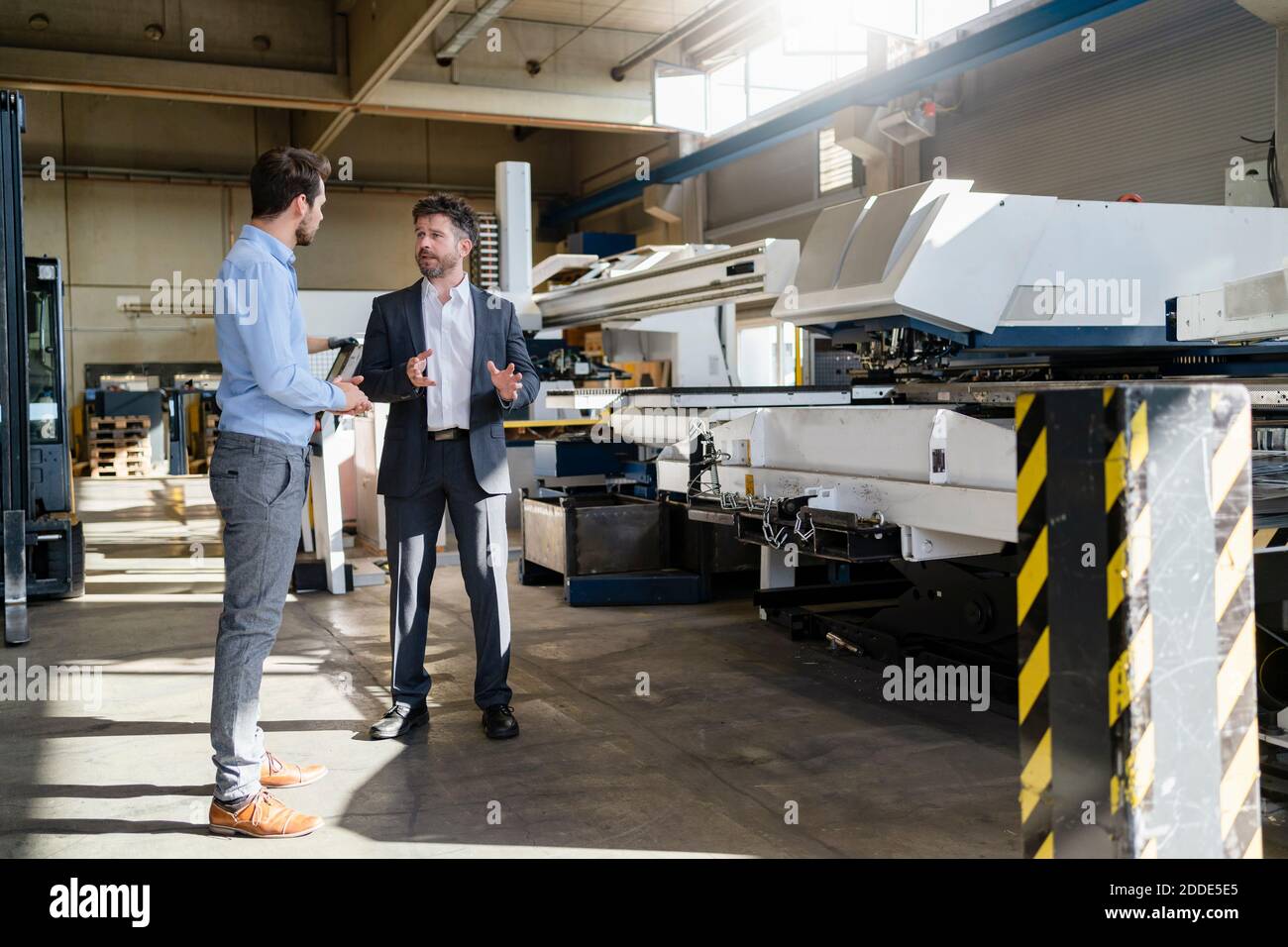 Male team having discussion while standing at factory Stock Photo - Alamy