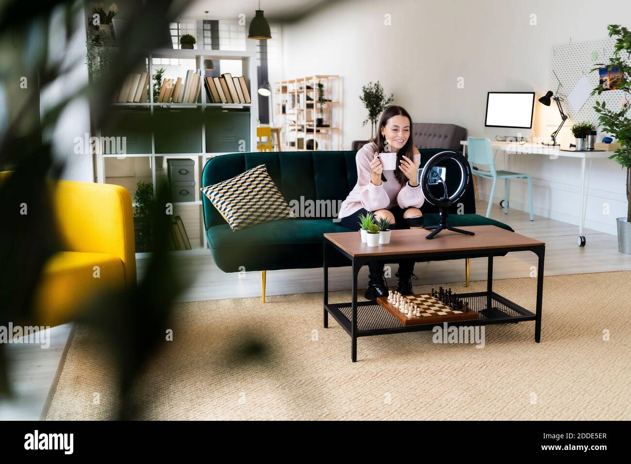 Smiling female influencer vlogging through smart phone and lighting ...