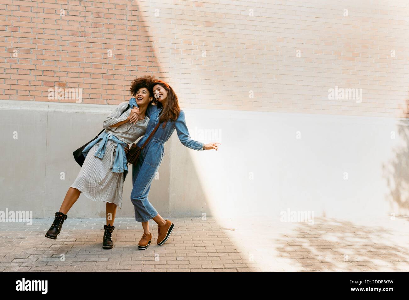 Playful friends standing against brick wall Stock Photo - Alamy
