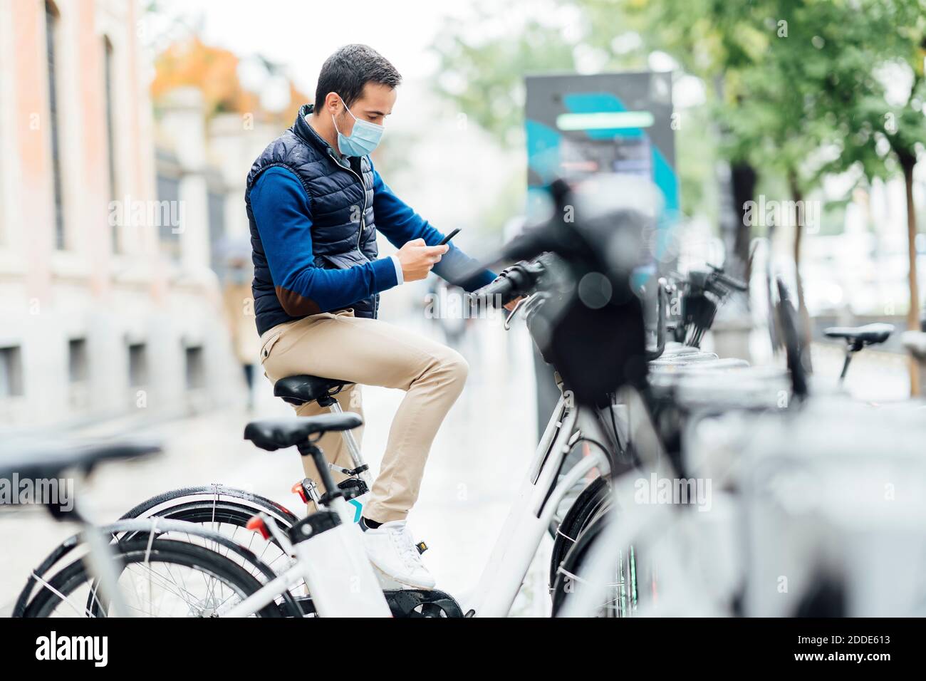 Young man using smart phone for payment of electric bicycle at parking ...