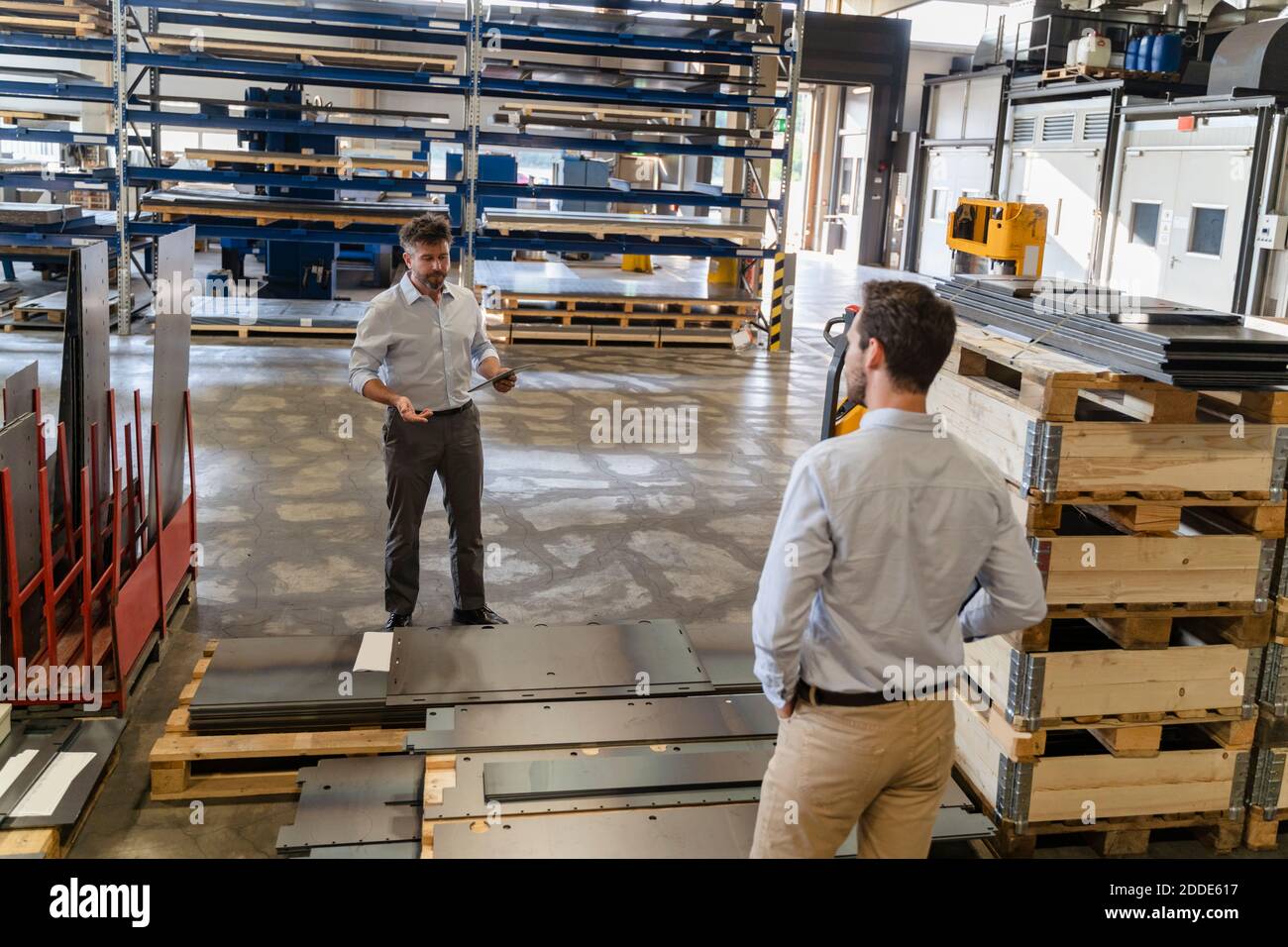 Business people standing by equipment while having discussion at ...