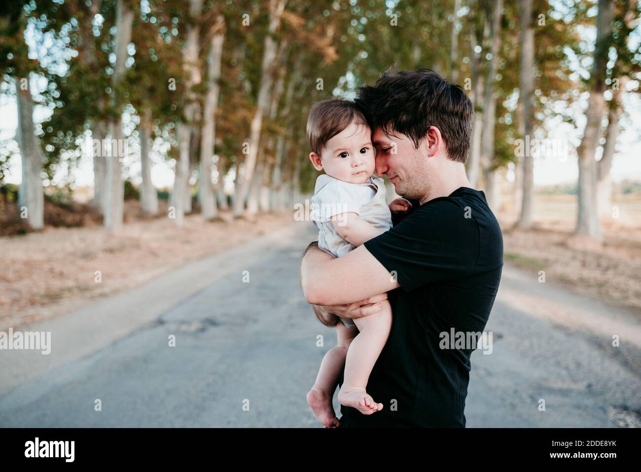 Smiling father embracing cute baby while standing on road outdoors ... Smiling father embracing cute baby while standing on road outdoors ...