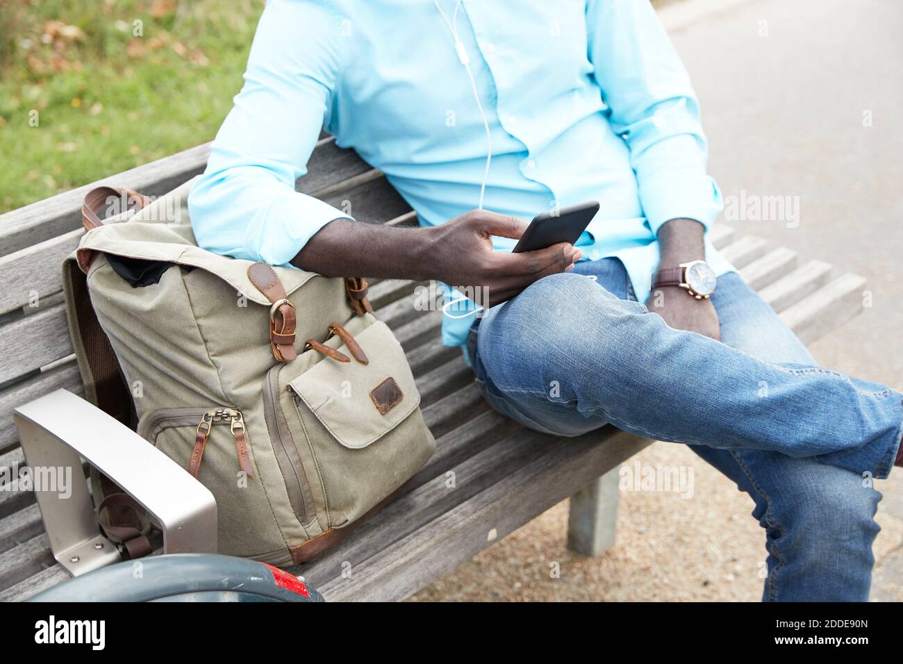 Man holding smart phone while sitting on bench Stock Photo - Alamy