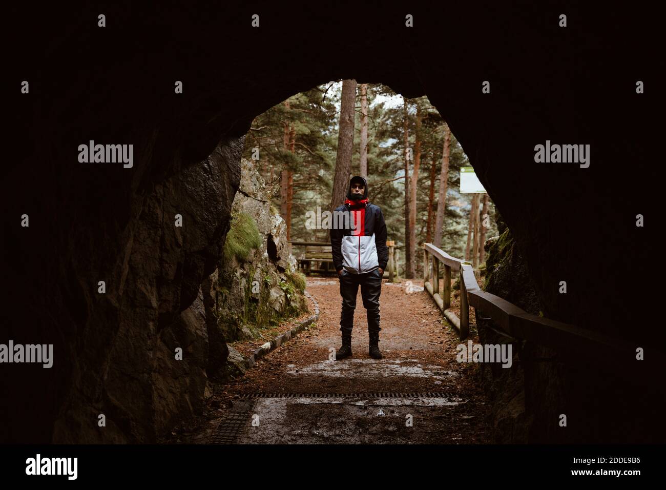 Young man standing in front of cave during autumn Stock Photo - Alamy