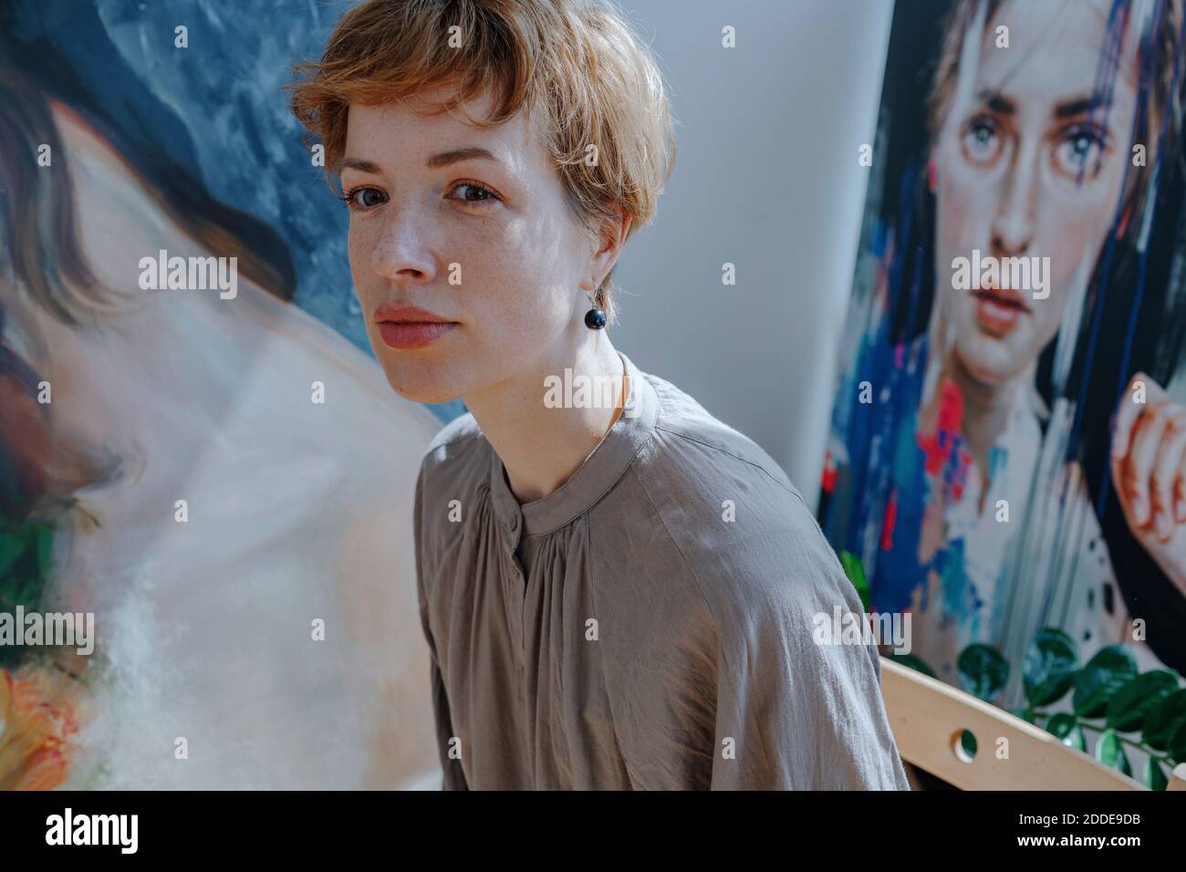 Female artist looking away against painting in art studio Stock Photo ...