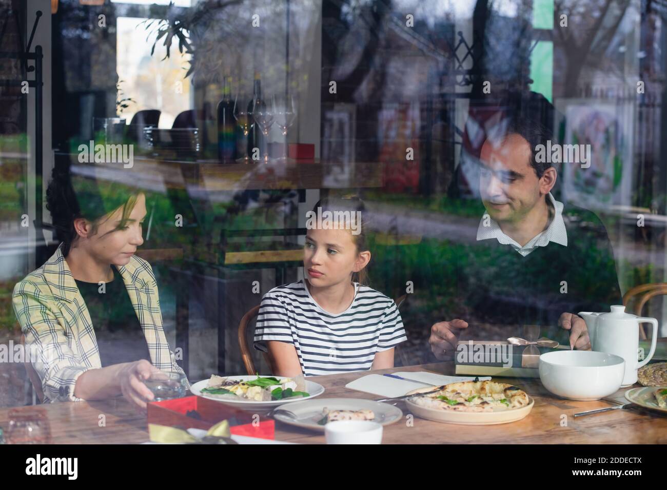 A girl having lunch with her parents, view through the window Stock ...