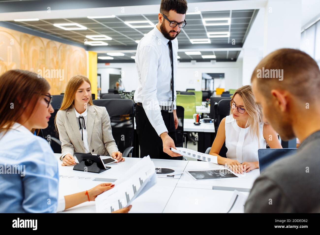 group of young leaders sitting at their desk discussing planning the ...