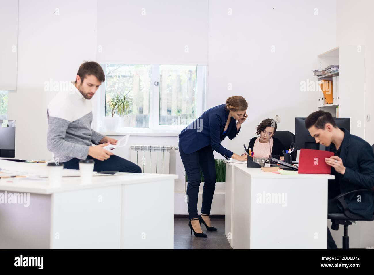 A busy work day in the modern office. Four people working in the office ...